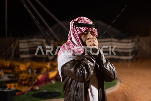 A Saudi Arabian Gulf man wearing a winter jacket and blowing with his ...