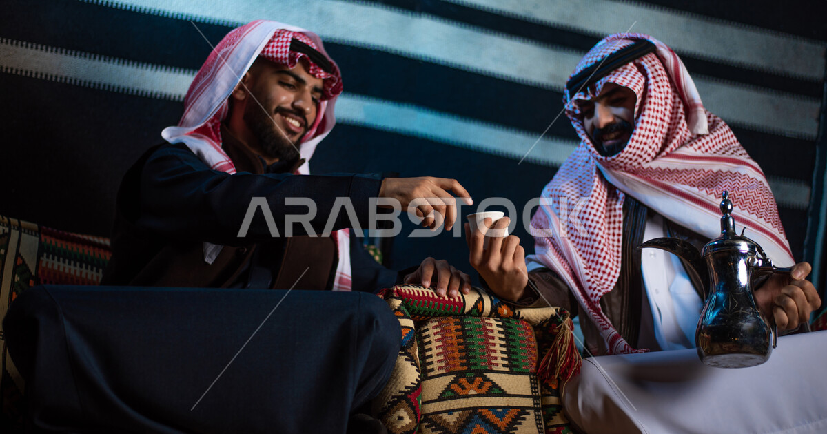 Two young Saudi Arabian Gulf men dressed in warm winter clothes ...