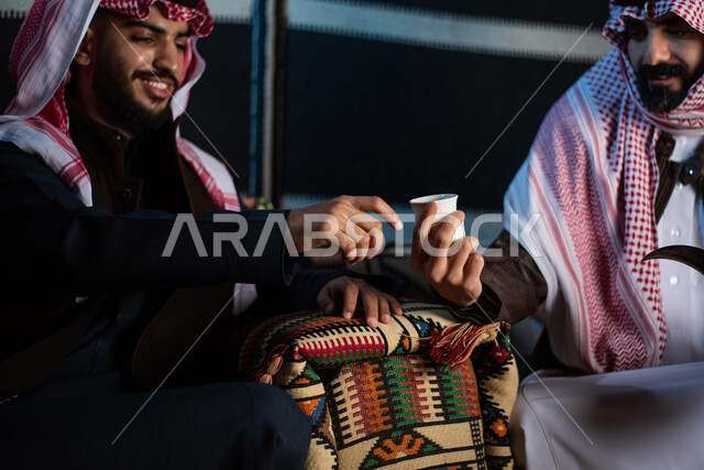 A close-up of two Saudi Arab Gulf men dressed in warm winter clothes, a ...