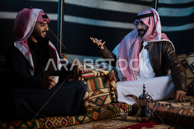 Two young Saudi Arabian Gulf men enjoying drinking Arabic coffee ...