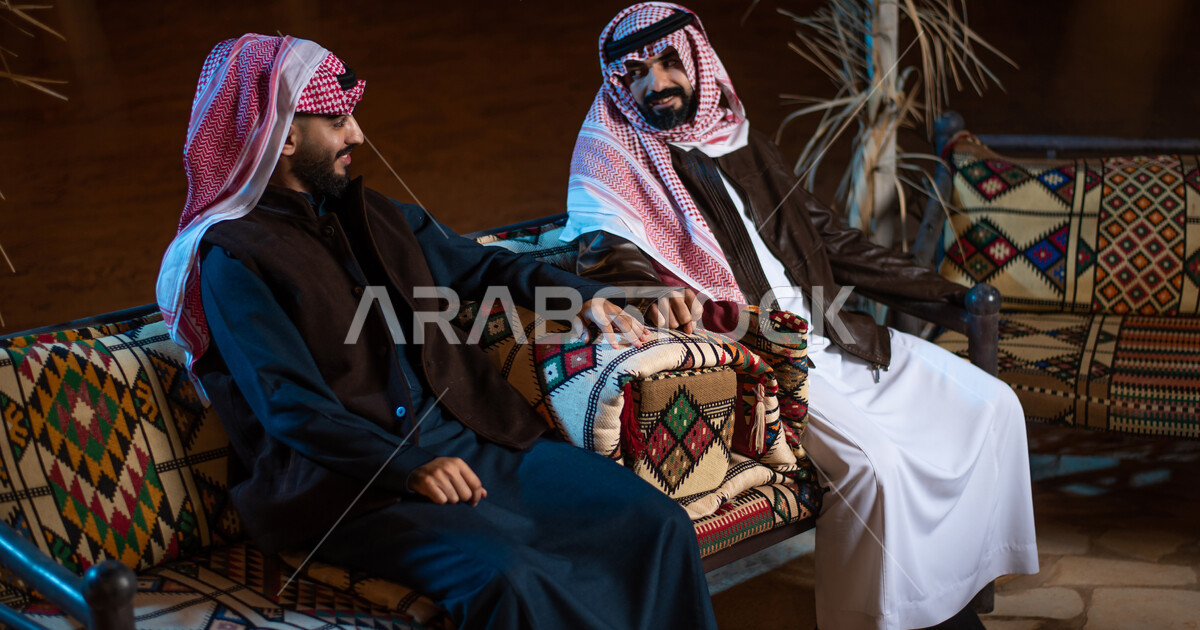 Two Saudi Arabian Gulf men dressed in warm winter clothes, enjoying a ...