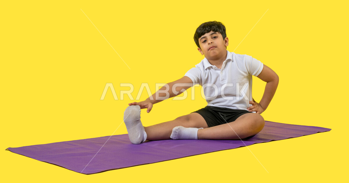 Portrait of an Arab Gulf boy wearing sports clothes, stretching and ...