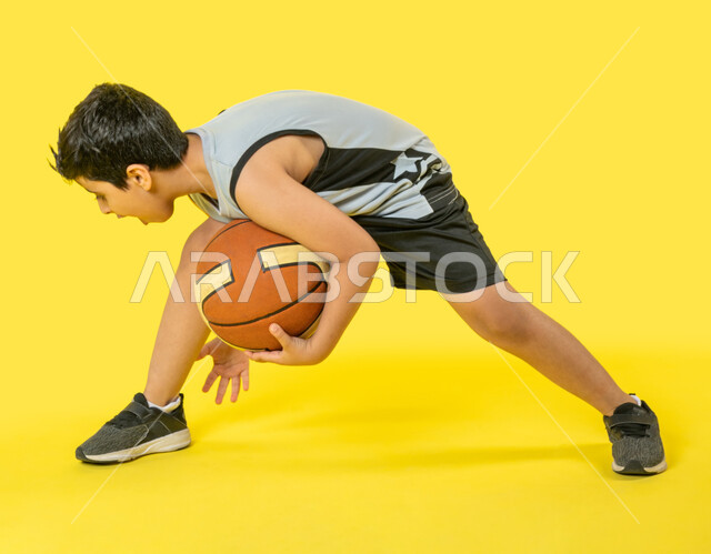 Practicing basketball exercises, a portrait of a Saudi Arabian Gulf boy ...