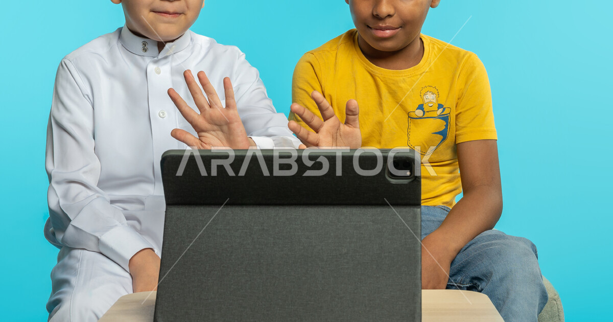 Portrait of two Saudi Arabian Gulf children using a tablet, making a ...