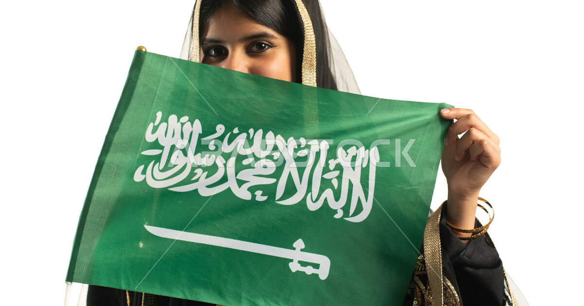Portrait of a Saudi Arabian Gulf girl, holding the Saudi flag, wearing ...