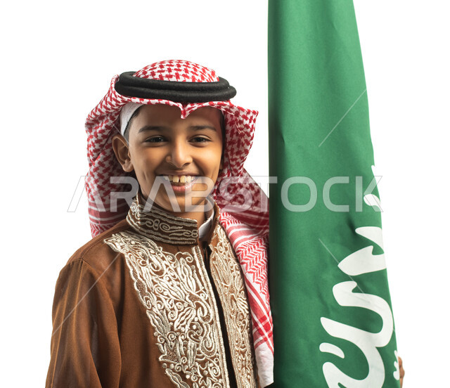 Portrait of a Saudi Arabian Gulf boy, holding the Saudi flag, wearing ...