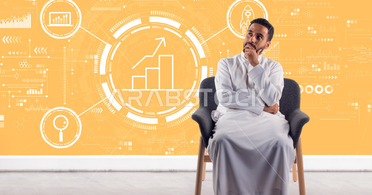 A Saudi Gulf Arab man sits on a chair and puts his hand on his chin ...