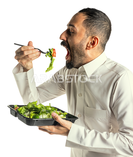 Portrait of a Saudi Arabian Gulf man eating a delicious vegetable salad ...