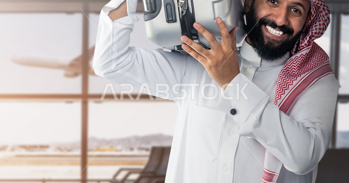 A Saudi Arabian Gulf man carrying a travel bag on his shoulder with ...