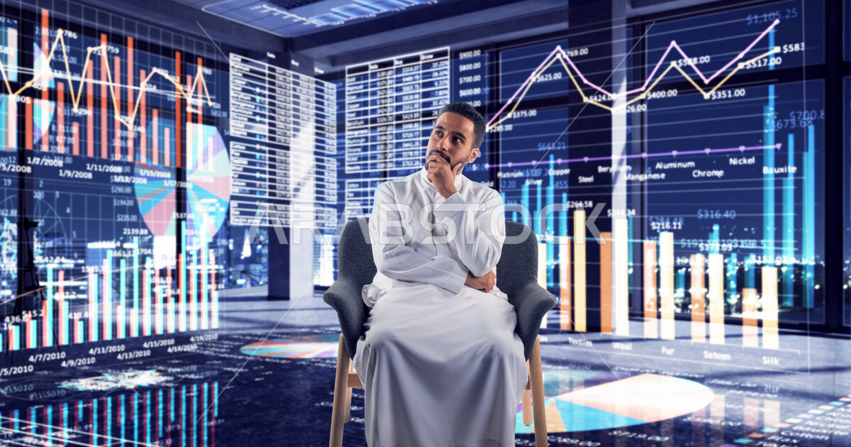 A Saudi Gulf Arab man sits on a chair and puts his hand on his chin ...