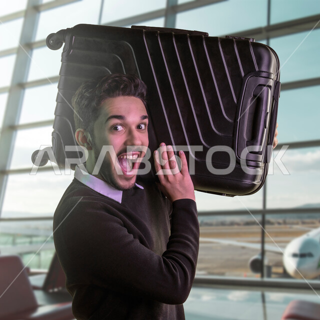 A young Saudi Arabian Gulf man carrying a travel bag on his shoulder ...