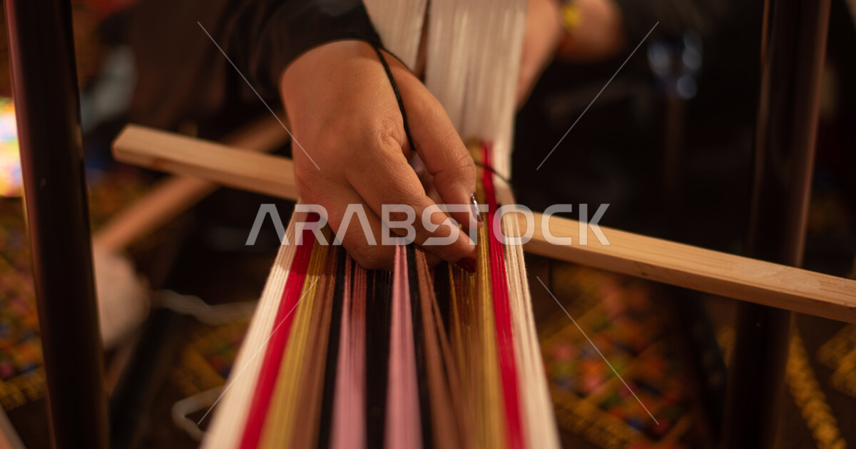 A close-up of the hand of a Saudi Arab Gulf woman who weaves and spins ...