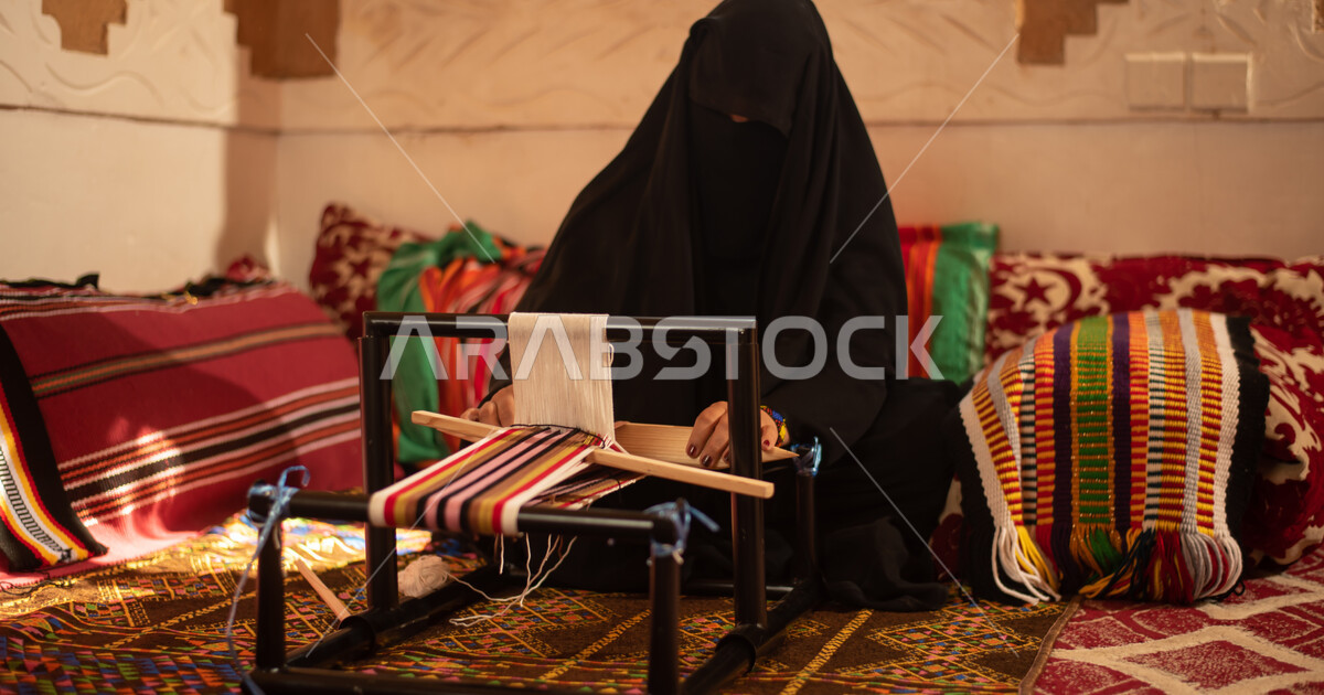 A Saudi Arab Gulf woman who wears a niqab knits and spins textiles and ...