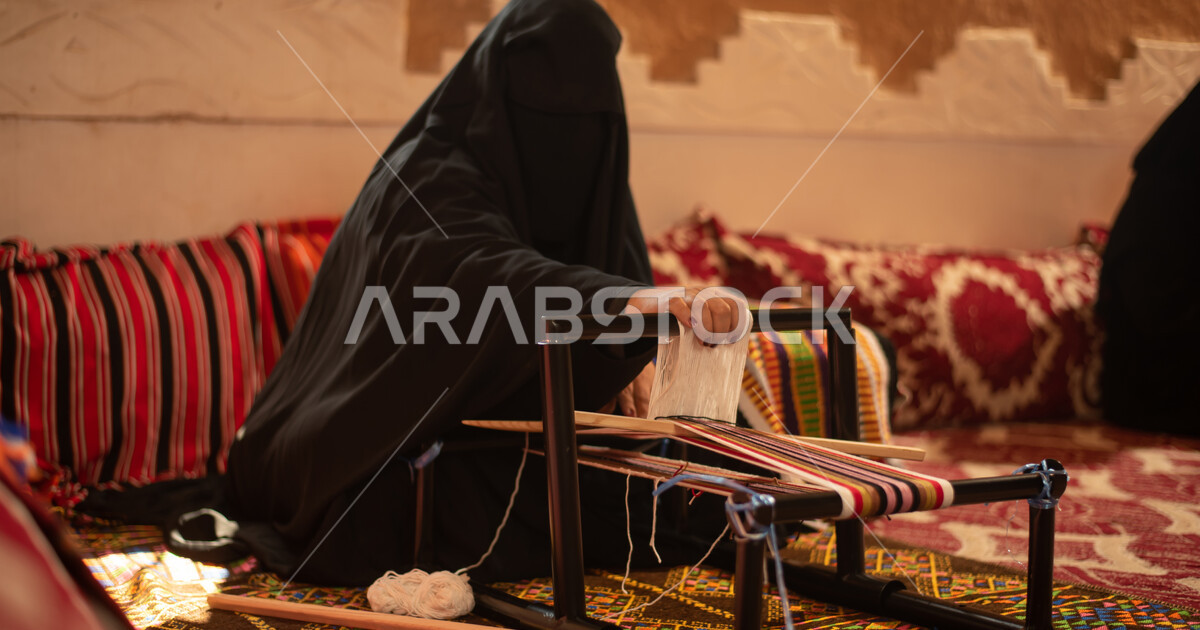 A Saudi Arab Gulf woman who wears a niqab knits and spins textiles and ...