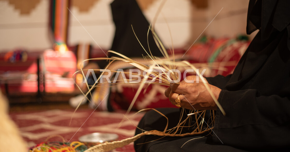 A Saudi Arab Gulf woman wearing a veil braids wicker palms, traditional ...