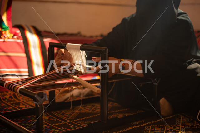 A Saudi Arab Gulf woman who wears a niqab knits and spins textiles and ...