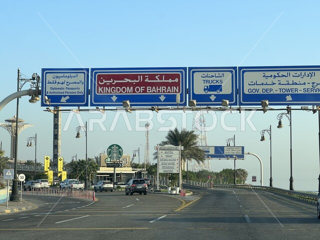 Guidance signs hanging on the road leading to the Kingdom of Bahrain ...
