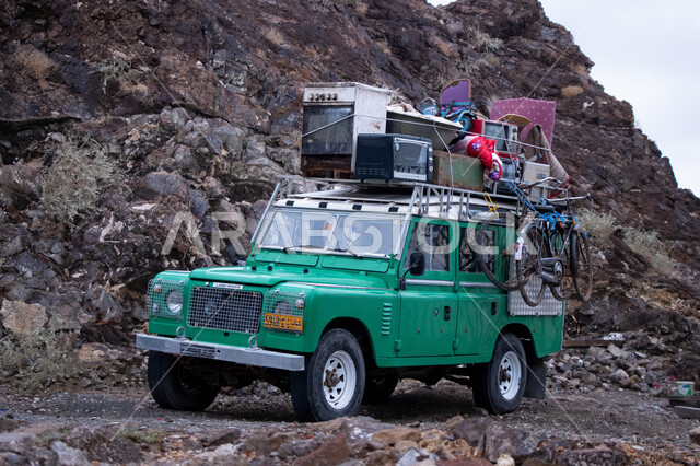An antique car loaded with old things standing on a rocky mountain full ...