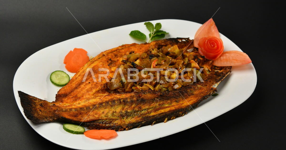 A plate of marinated fried fish on a blackened surface, seafood, arabic ...