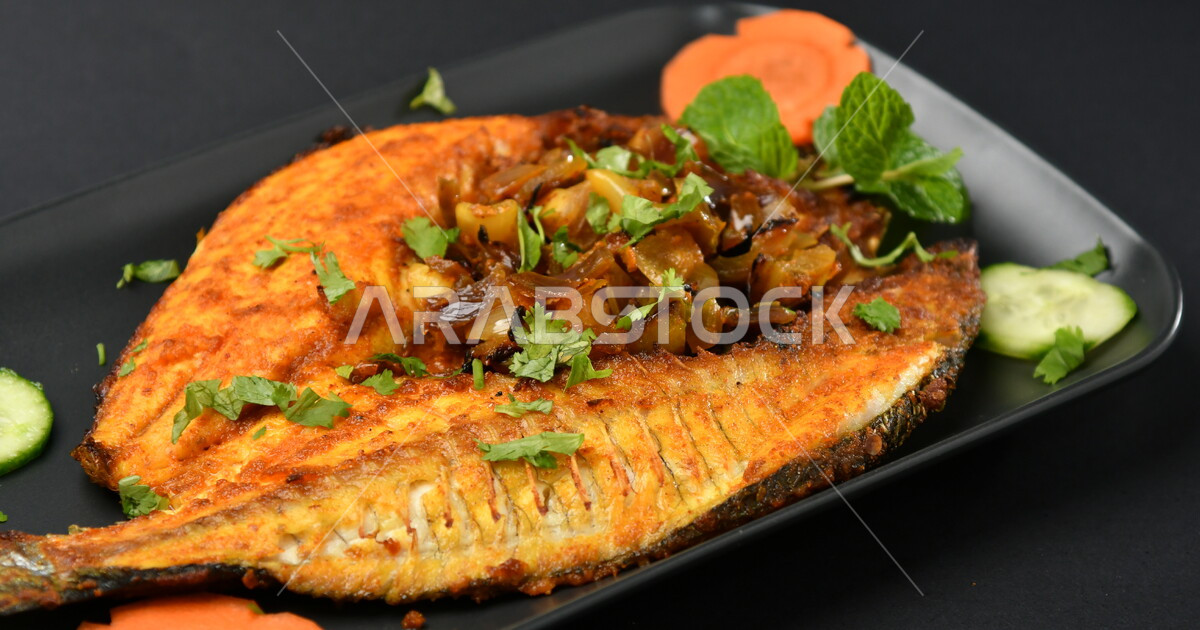 A plate of marinated fried fish on a blackened surface, seafood, arabic ...