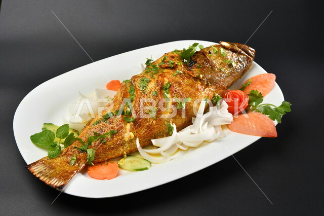 A plate of marinated fried fish on a blackened surface, seafood, arabic ...