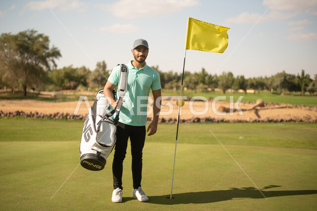 A Saudi Arabian Gulf man wearing a sports uniform and carrying a golf ...