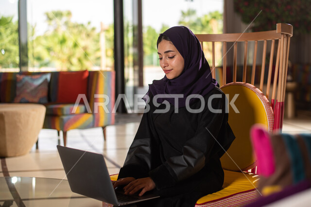 An Arab, Saudi, Gulf woman using a laptop, completing work tasks ...