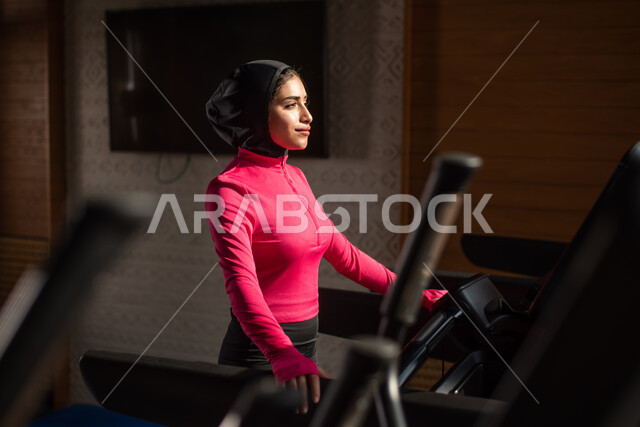 A veiled Saudi Gulf Arab woman wears sportswear and exercises, using ...