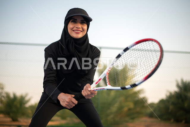 A Saudi Arab Gulf woman playing tennis, playing tennis in public courts ...