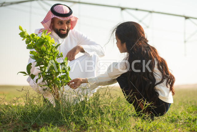A Saudi Arabian Gulf man with his daughter in an agricultural field ...