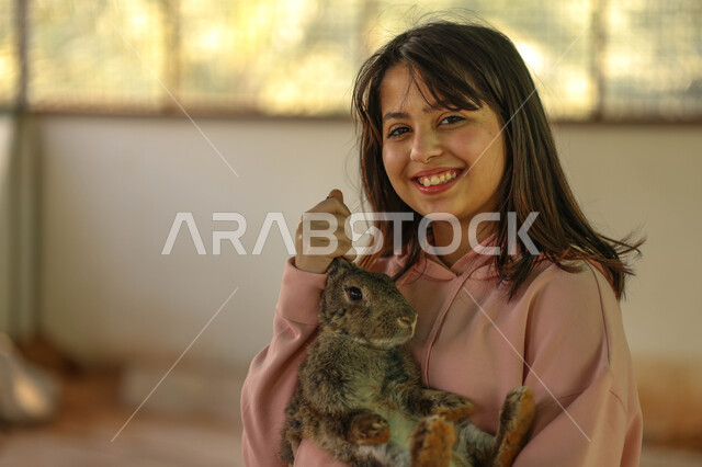 A Saudi Gulf Arab girl carrying a rabbit, spending fun times in the zoo ...