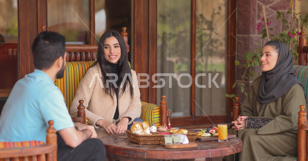A man and two Saudi Arabian Gulf women enjoying an exchange of ...