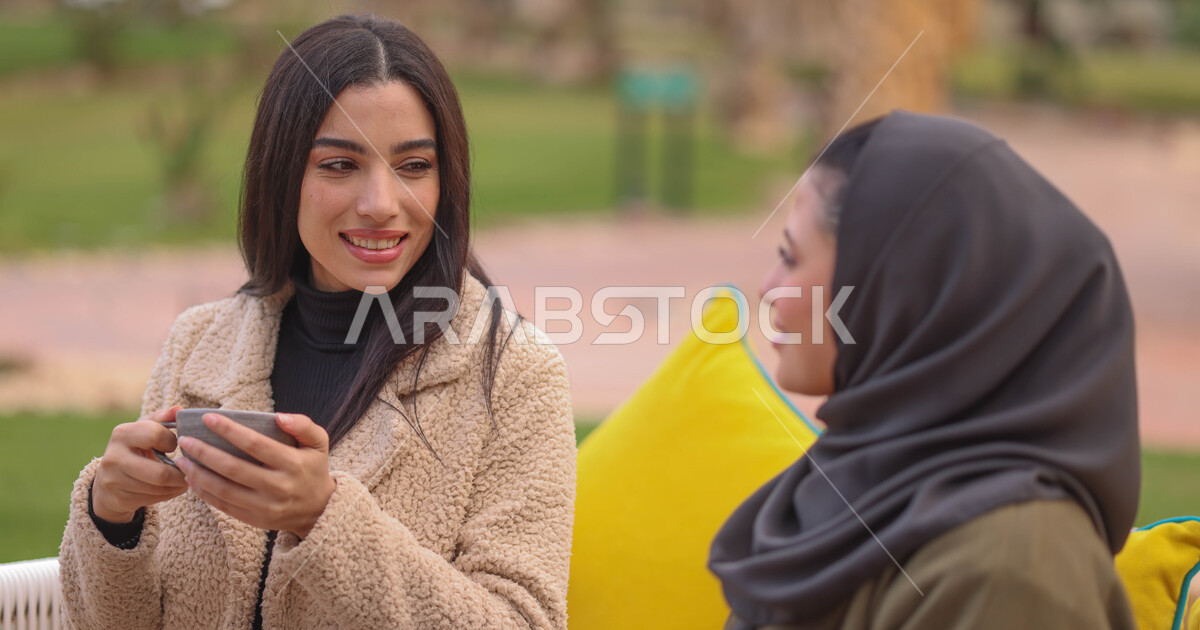 Two Saudi Arabian Gulf female friends enjoy exchanging conversation ...