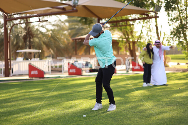 A Saudi Arab Gulf man wearing a sports uniform, playing golf on large ...