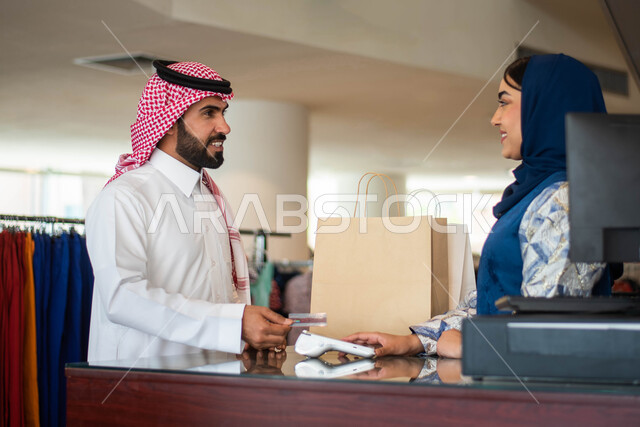 Paying the account for purchases in the clothing store, a Saudi Arabian ...