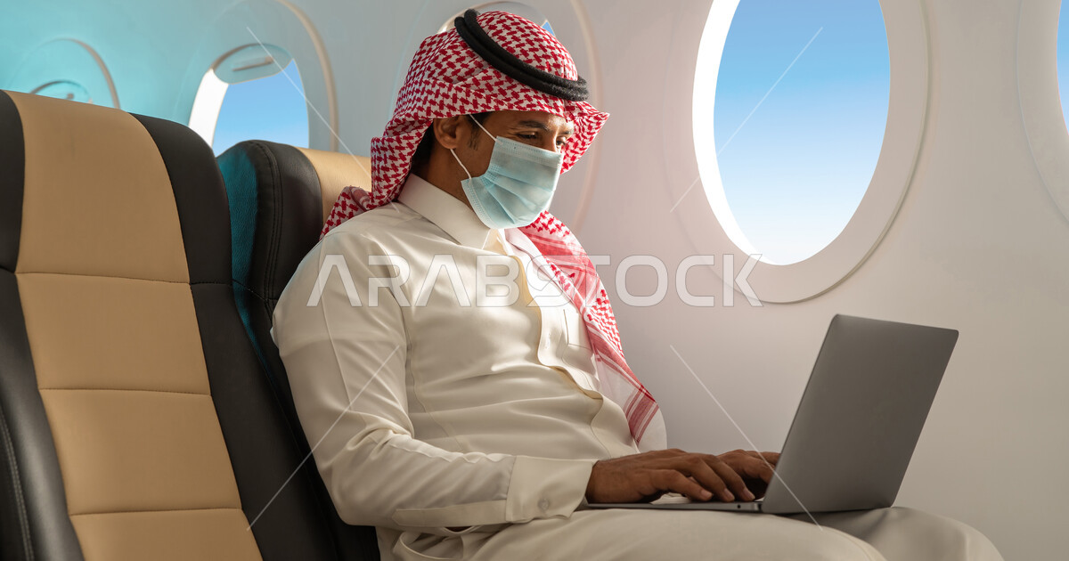 A Saudi Gulf Arab businessman wearing a medical mask, sitting in the ...