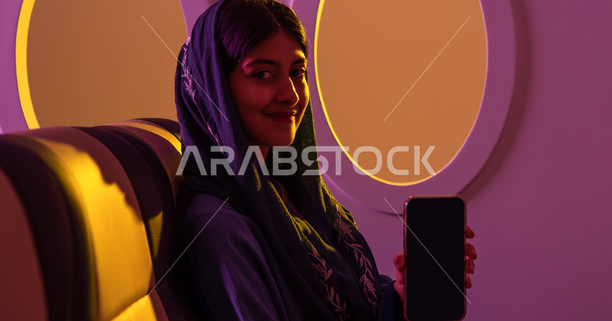 A Saudi Gulf Arab woman sitting on the plane, a blank black screen ...