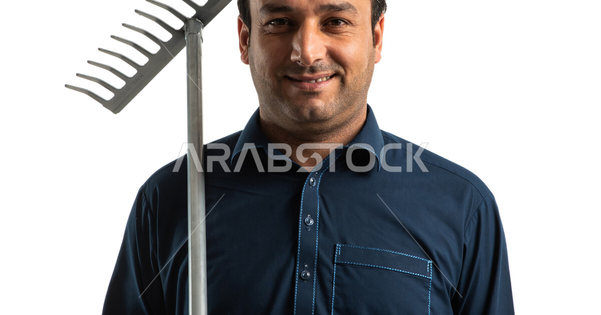 Portrait of a Pakistani farmer holding a rake in his hand and wearing ...