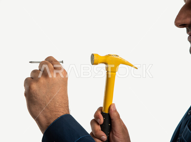 Close-up of a Pakistani construction worker hammering nails with a ...