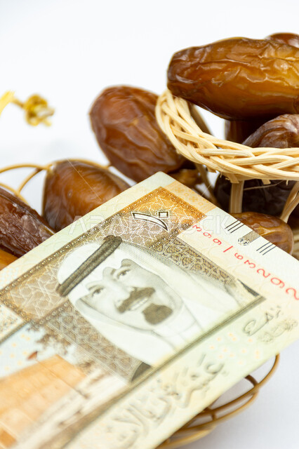 A close-up of dates with a 10 Saudi riyal banknote, Deglet Nour dates ...