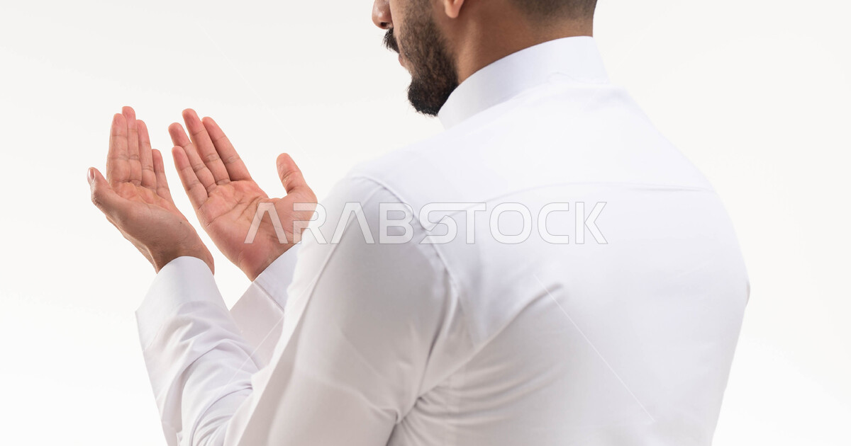Portrait of a Saudi Arab Gulf man, wearing a white dress, raising his ...