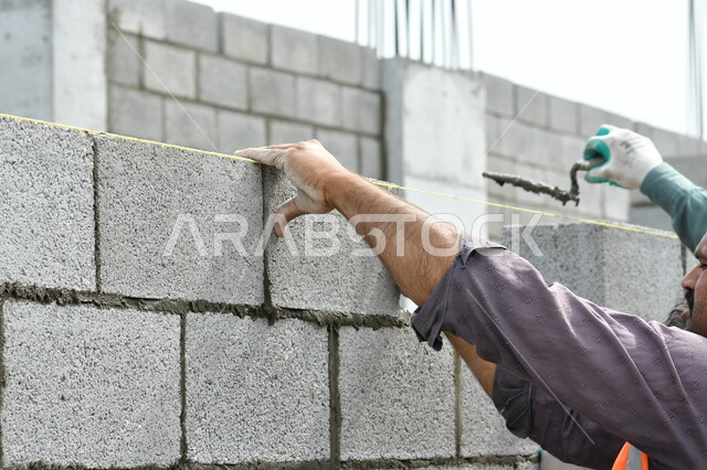 Close up of a construction worker building a brick and cement wall ...