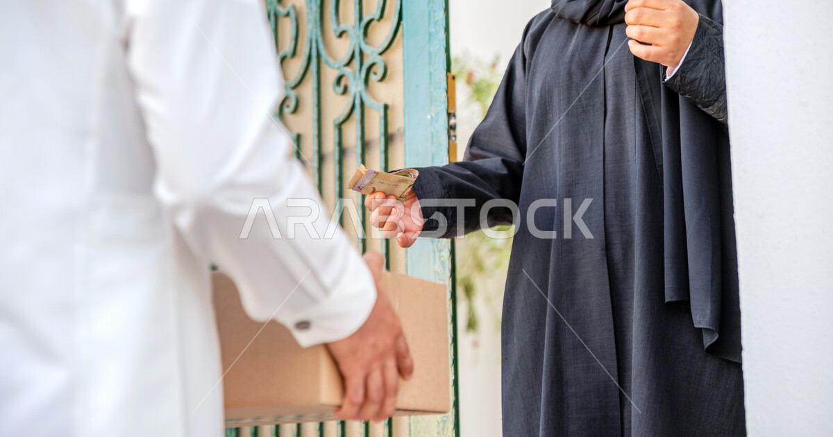 A young Saudi Arab Gulf man holds the parcel in his hand to deliver it ...