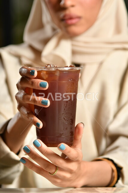 Portrait of a Saudi Arabian Gulf woman holding a cup of cold coffee in ...