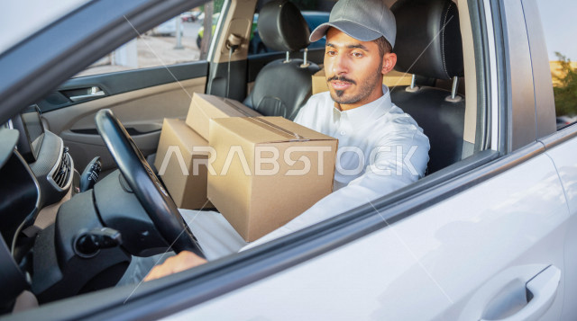 A young Saudi Arab Gulf man sitting in a car with delivery parcels, the ...