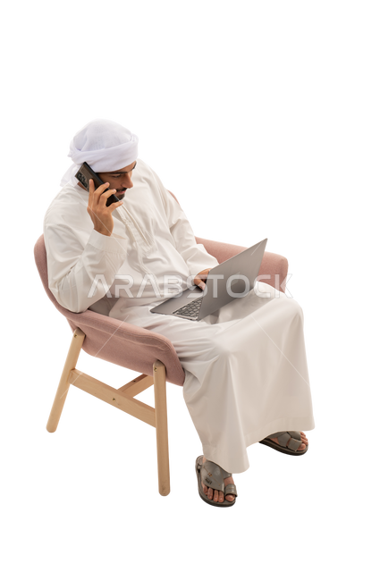 Portrait of an Arab Gulf Emirati man sitting on a chair using a ...