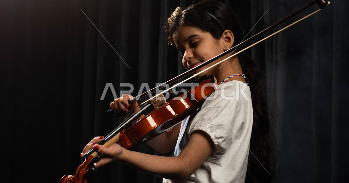 Practicing the hobby of playing the violin, a Saudi Gulf Arab girl, an ...