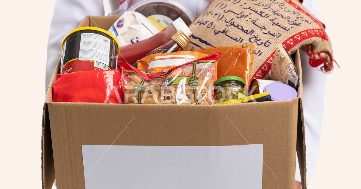 A close-up of a Saudi Arabian Gulf man carrying a food box, donating to ...