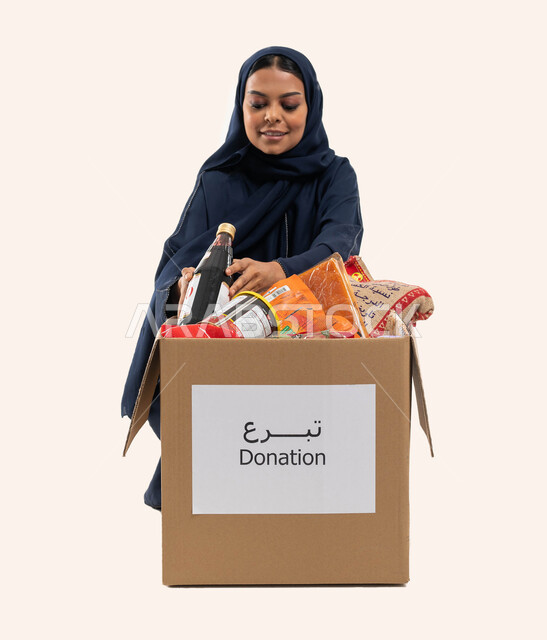 Portrait of a Saudi Arab Gulf woman filling the food box, donating to ...