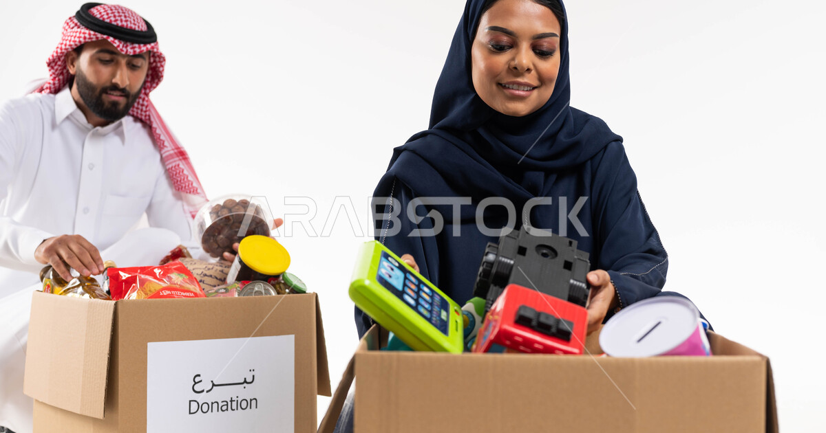 Portrait of a Saudi Arabian Gulf man and woman, donation box full of ...
